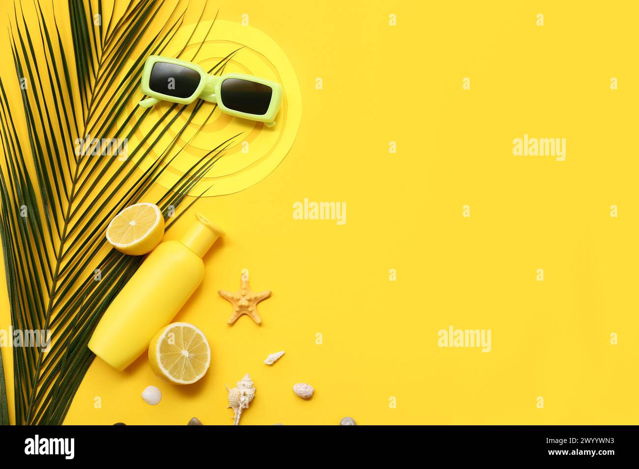 Bottle of sunscreen cream, lemon, sunglasses, paper sun figure, leaf ...