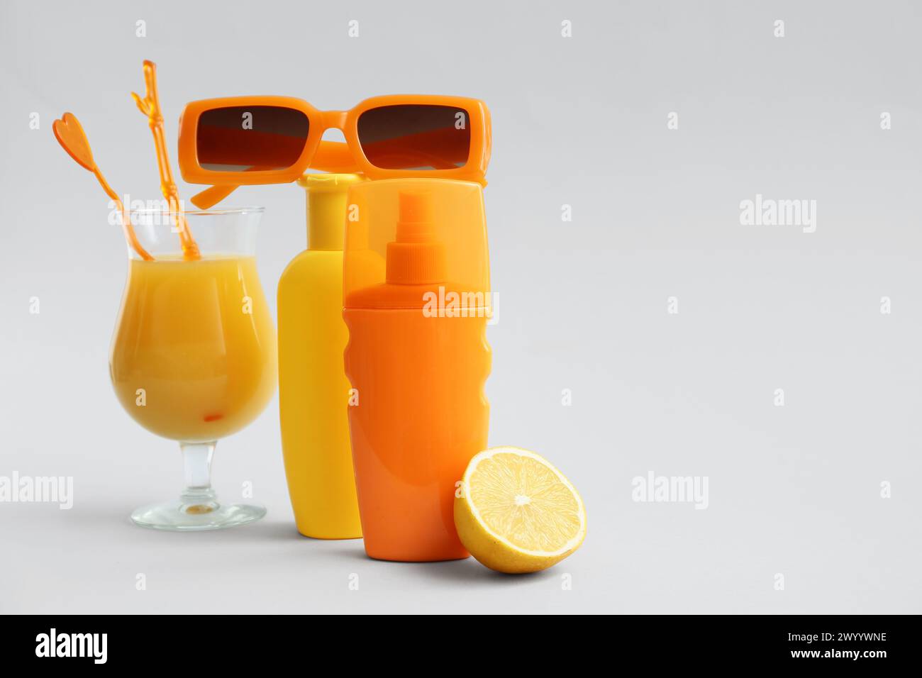 Bottles of sunscreen cream, glass of juice, lemon and sunglasses on ...