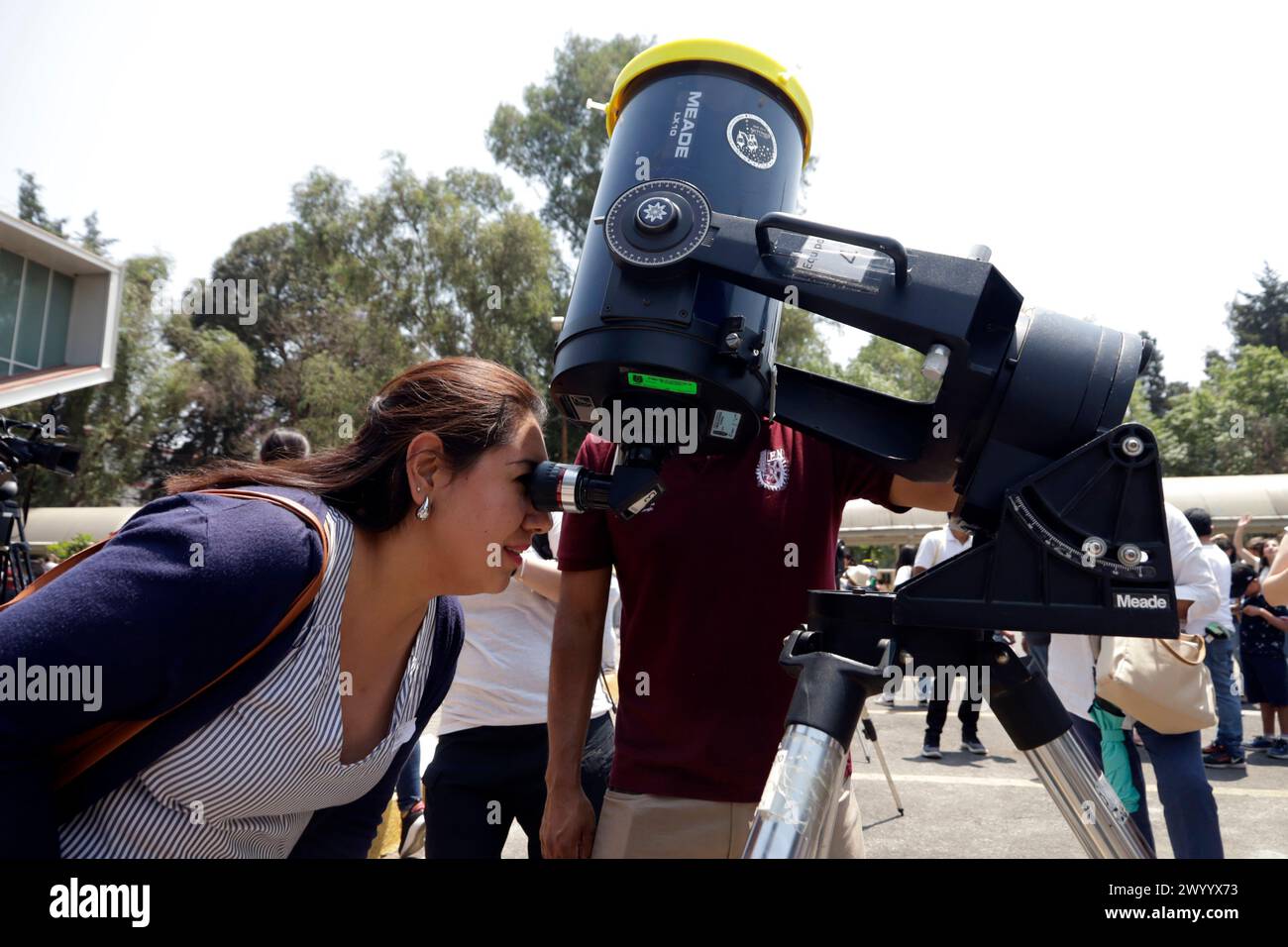 A person observes the solar eclipse through a telescope during the ...