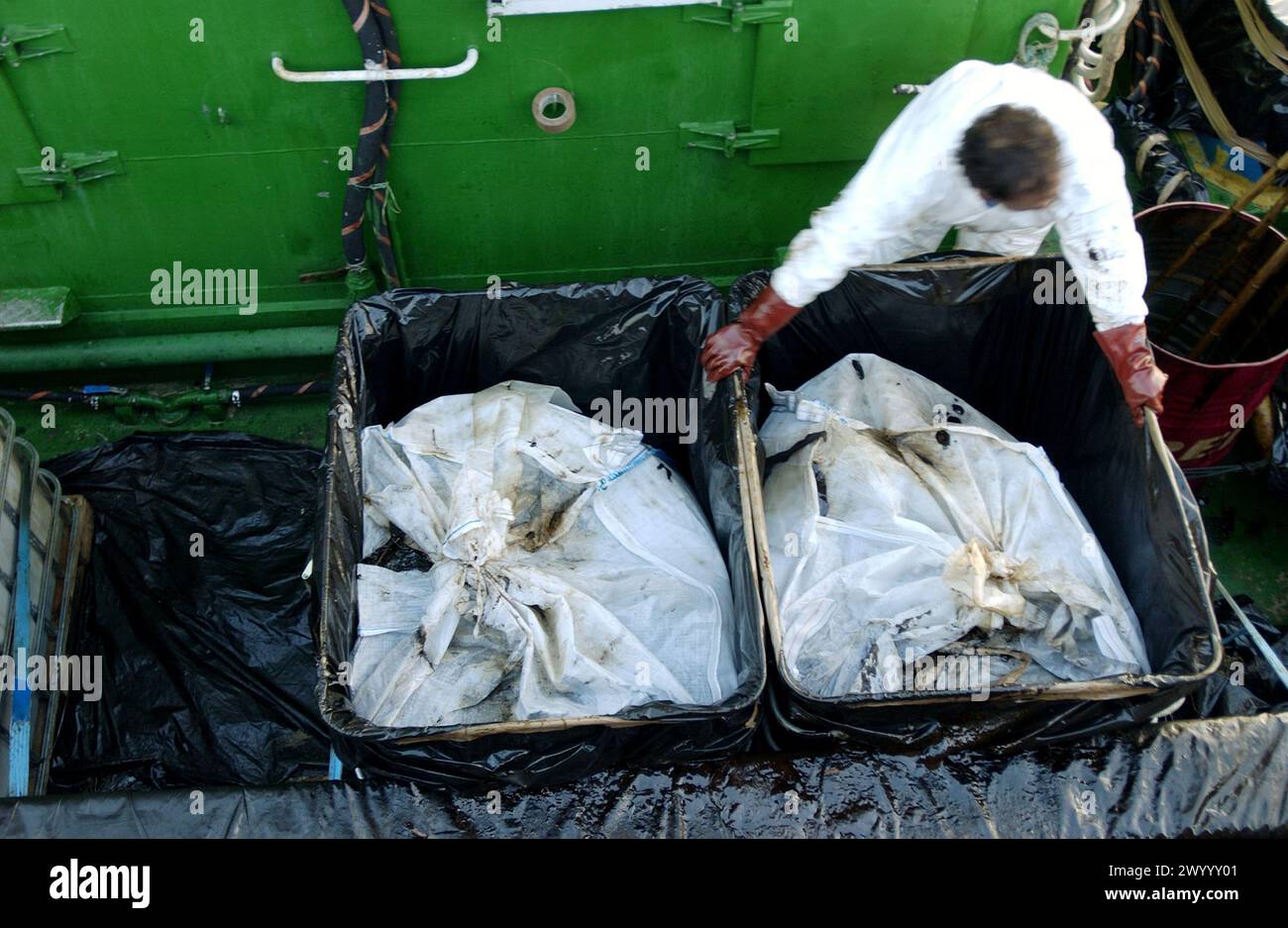 Fishermen dressing protective clothes gathering the fuel spill ...