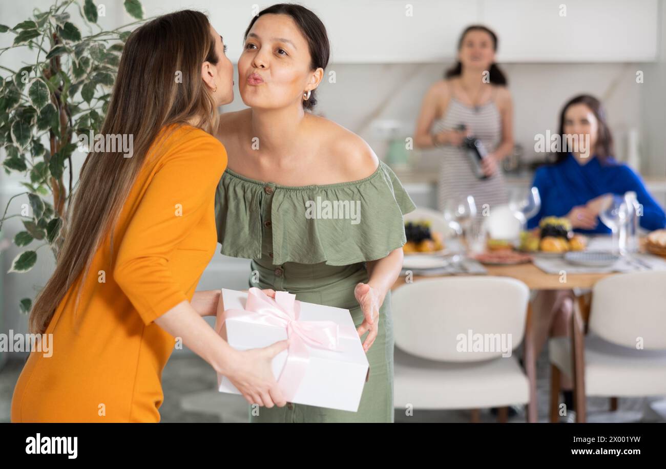 Group of women greeting each other and giving gift Stock Photo - Alamy