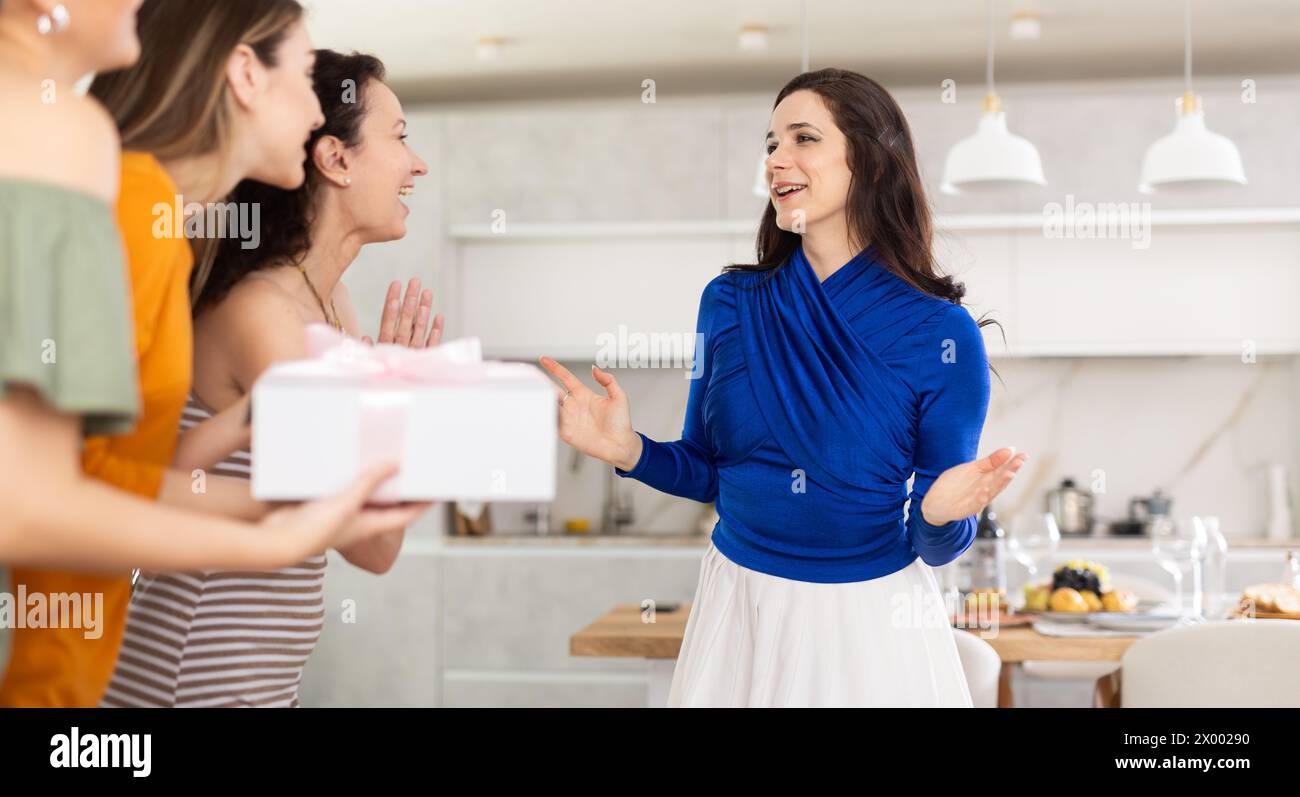 Happy brunette receiving unexpected gift from besties at birthday bash ...