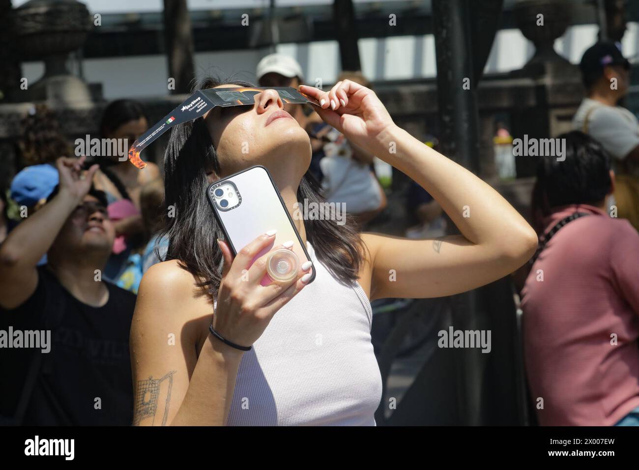 A woman watches the solar eclipse through a special viewing glasses ...