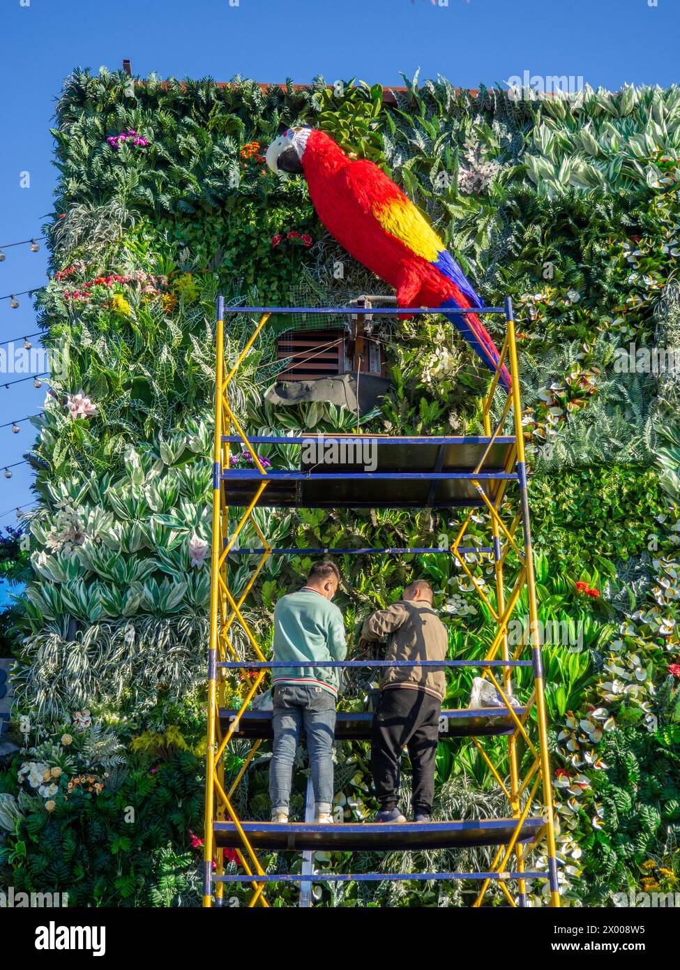 facade of the building is decorated with artificial birds. Parrots made ...