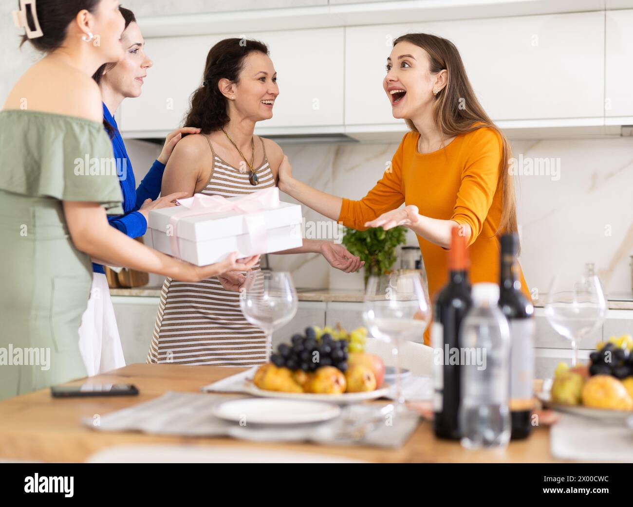 Group of women greeting each other and giving gift Stock Photo - Alamy