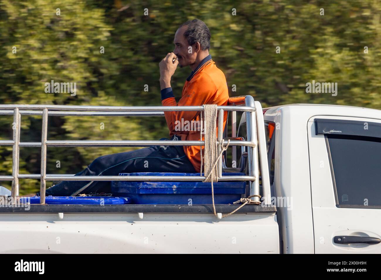 THAILAND, MAR 23 2024, A man sits in the cargo space of a fast-moving ...