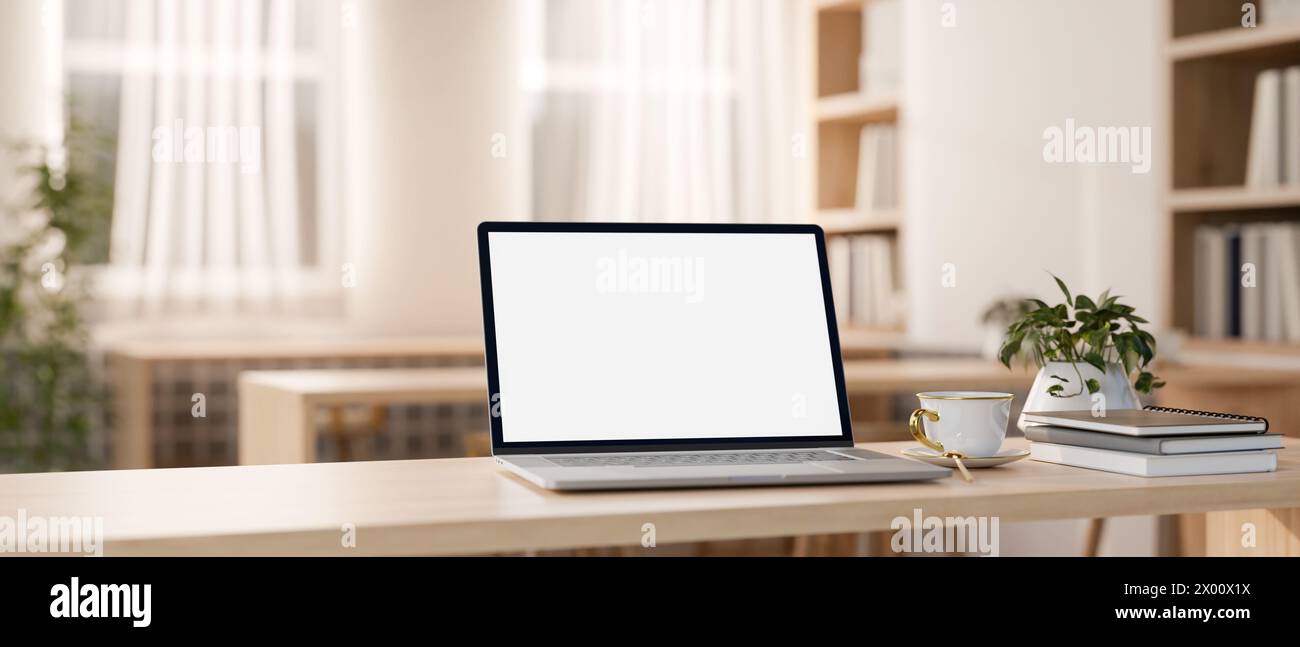 A white-screen laptop computer on a wooden table in a beautiful ...