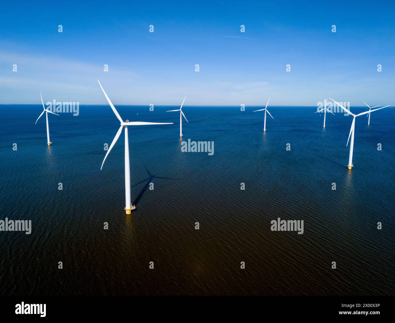 A group of wind turbines stand tall in the ocean, harnessing the power ...