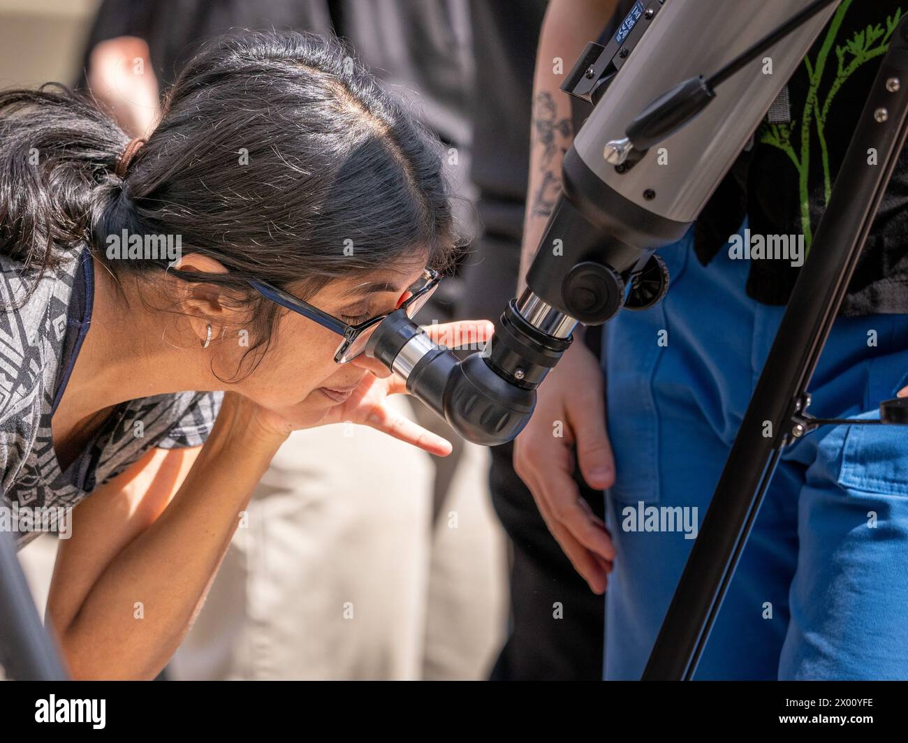 A girl looks through a telescope set up at the park for guests to watch ...