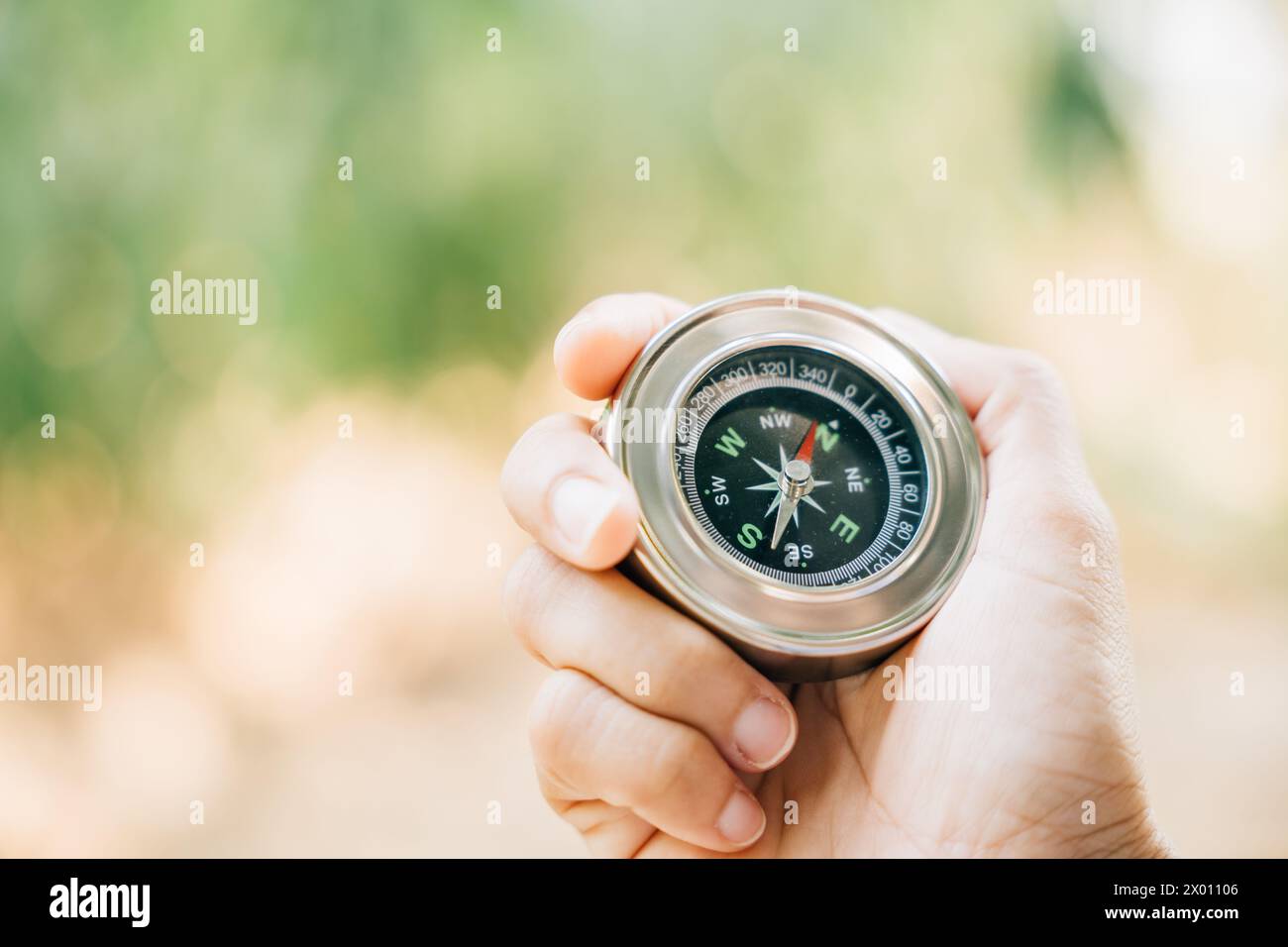 Hiker searches for direction in the forest holding a compass to ...