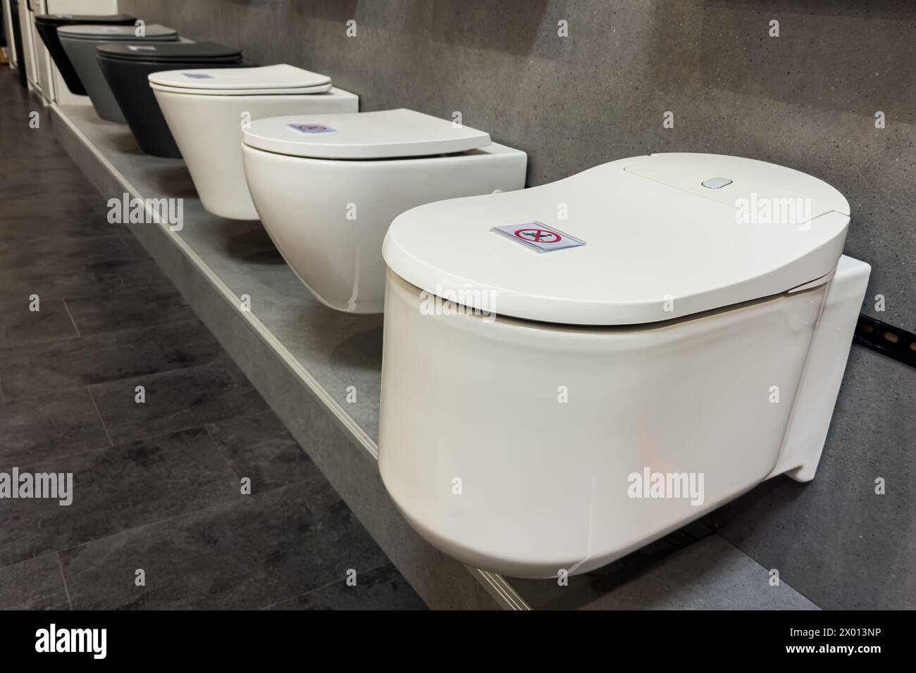 Ceramic toilet bowls of different types on a shop window. Sale of ...