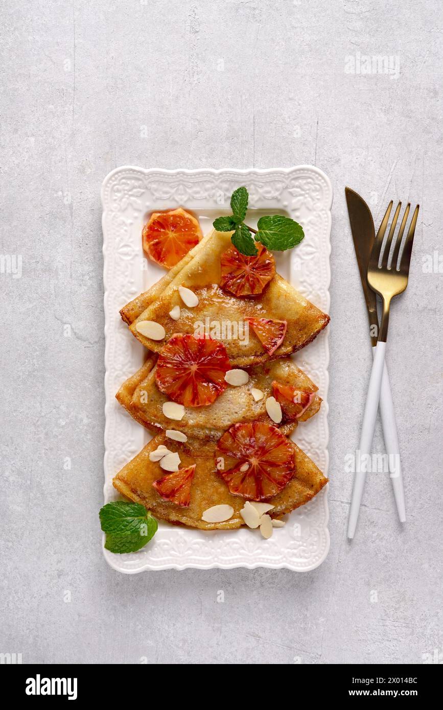 Crepes with Orange Sauce on a white rectangular plate. Traditional ...