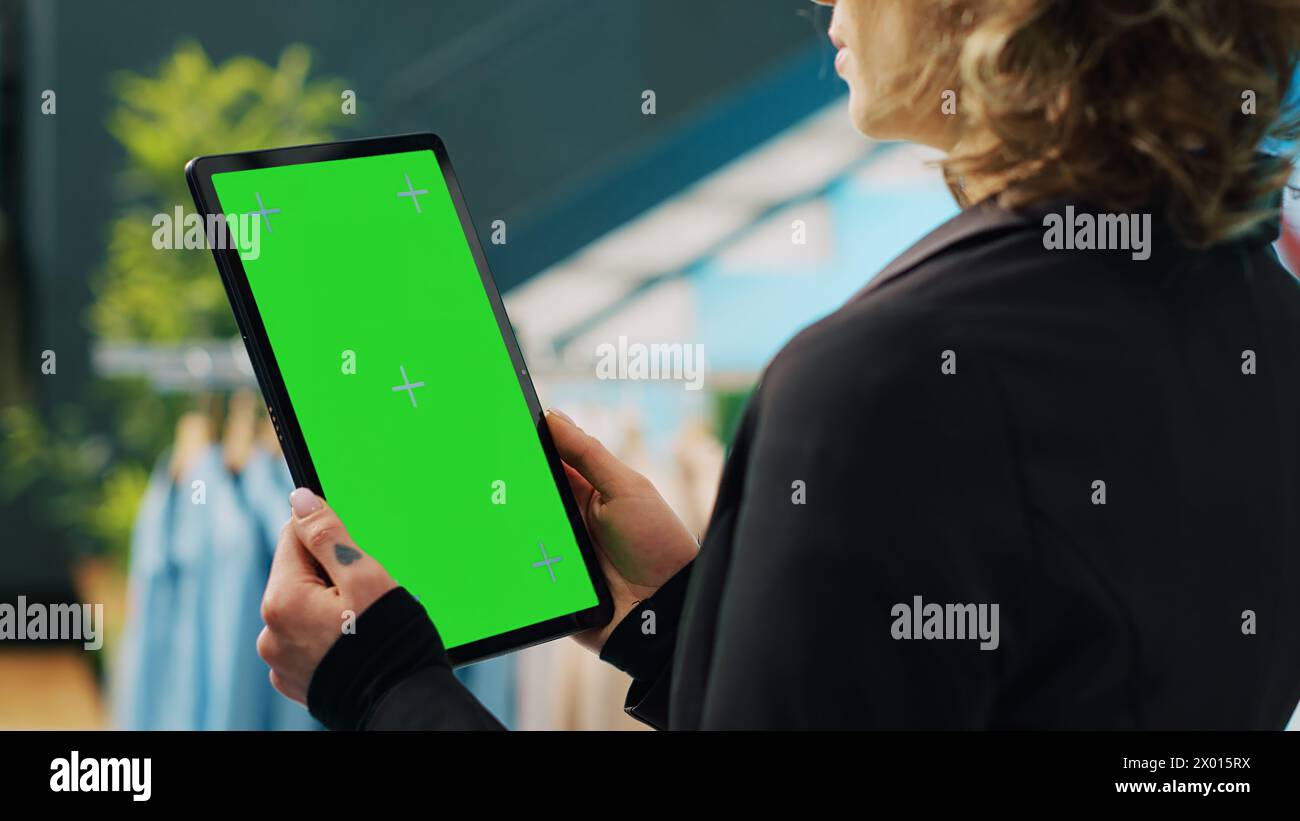 Store employee using tablet running greenscreen layout in fashion ...