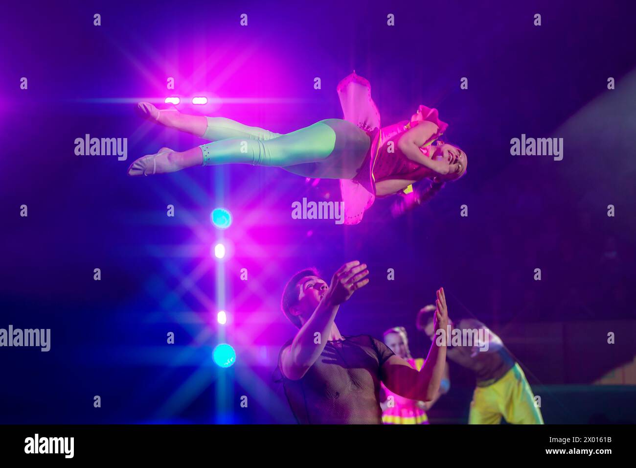 An acrobat in flight performs a complex trick in the rays of circus ...