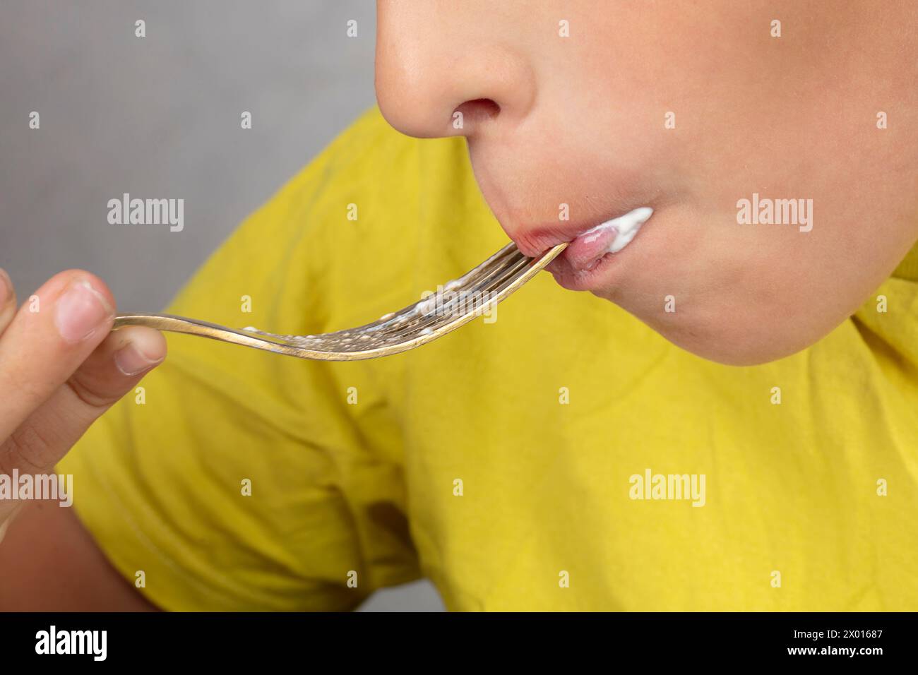 A child, whose face is not visible, holds a fork in his mouth Stock ...