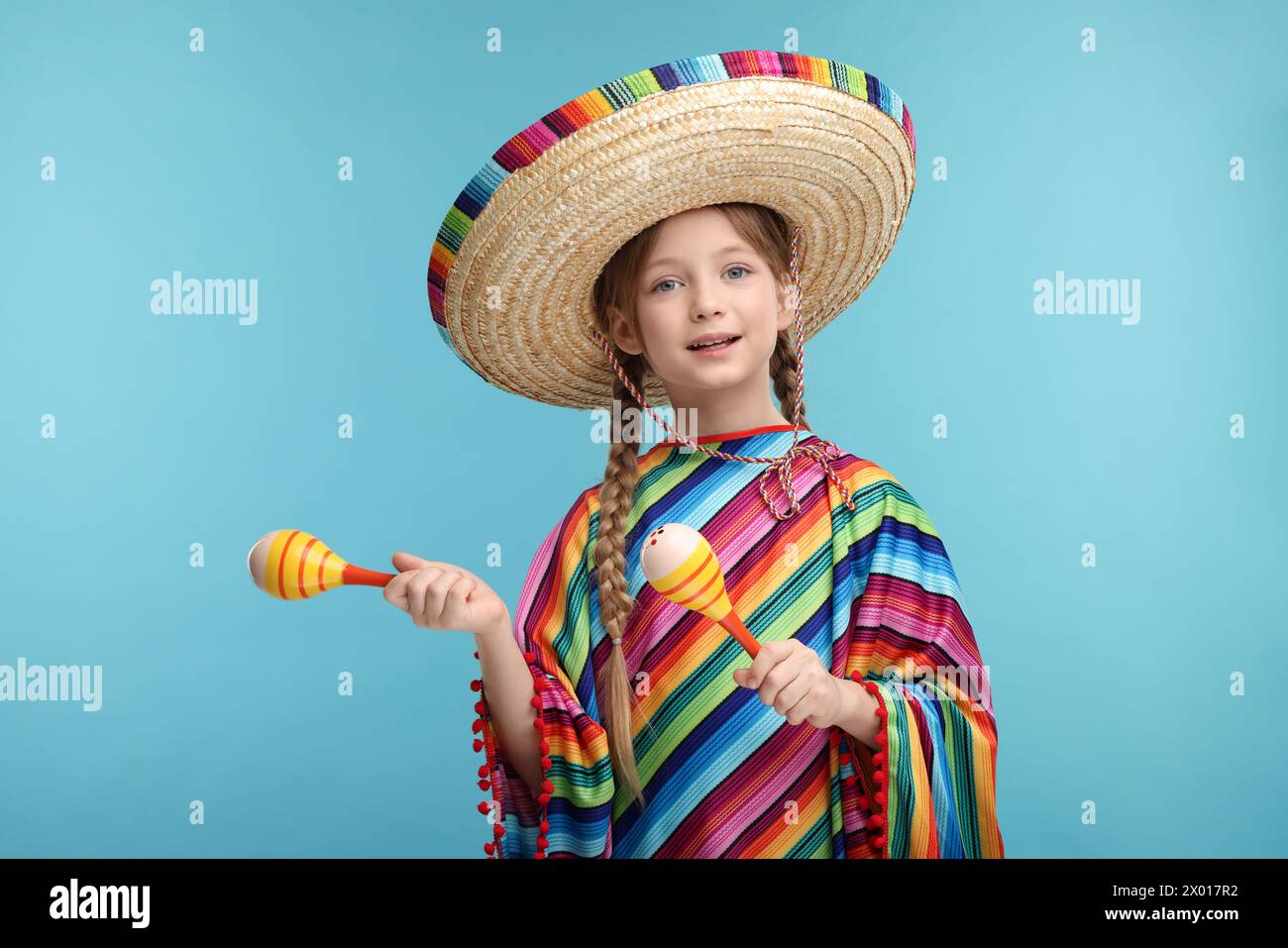 Cute girl in Mexican sombrero hat and poncho dancing with maracas on ...