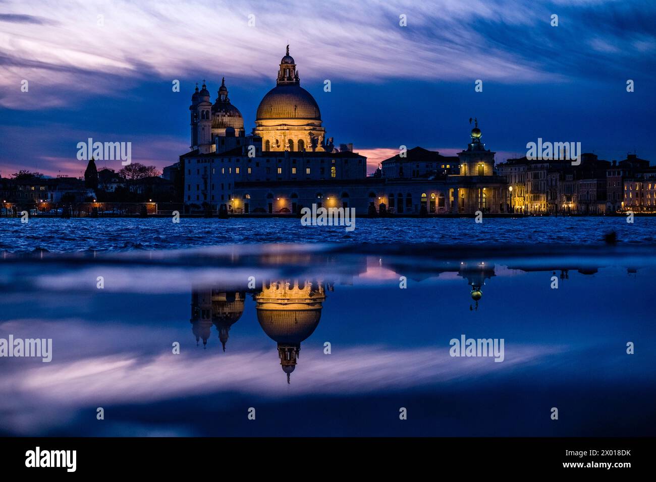 Basilica di Santa Maria della Salute at sunset, seen across the Canale della Giudecca, reflected ...