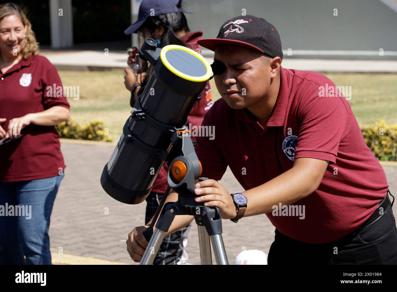 Non Exclusive: A person observes the solar eclipse through a telescope ...