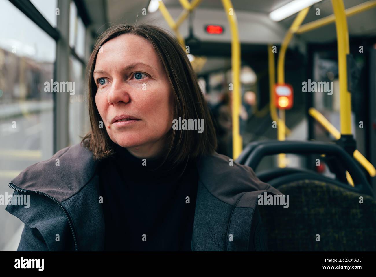 Contemplative adult caucasian woman riding public transportation bus ...