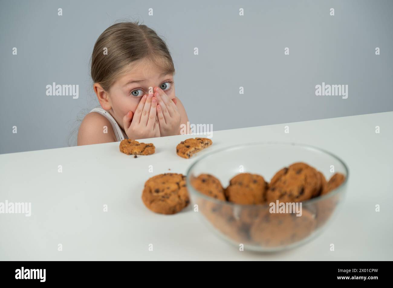 A little girl tries to steal cookies from the table Stock Photo - Alamy