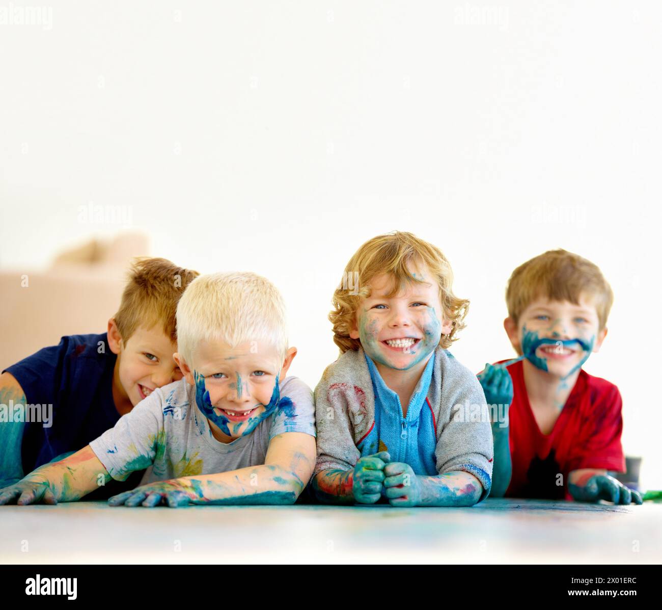 Child, paint and mess or playing portrait, happy boys in preschool or ...