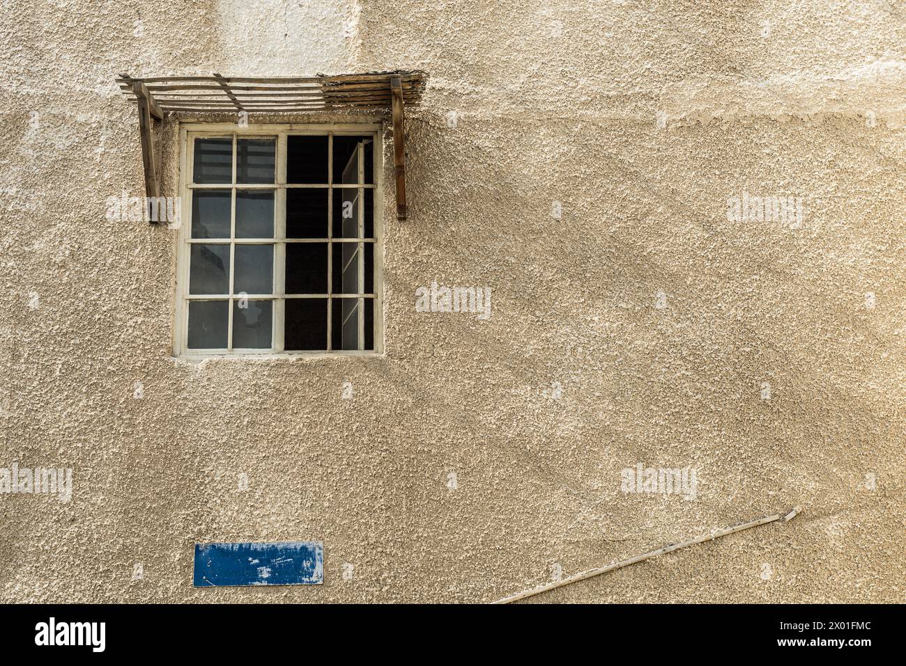 An open window with a shade from the sun casting shadows along a ...