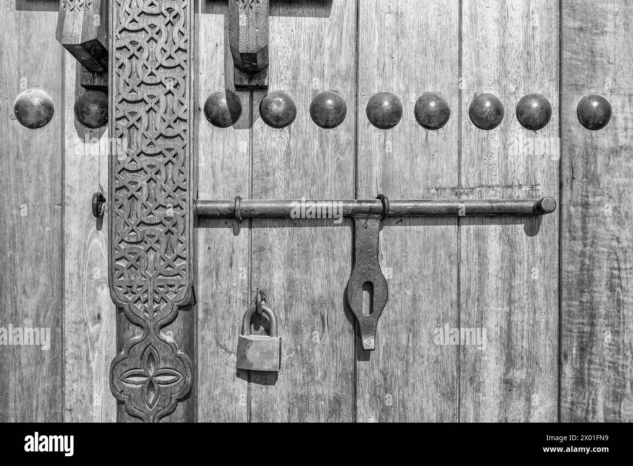 A monochrome image showing detail of a carved wooden door and lock at ...