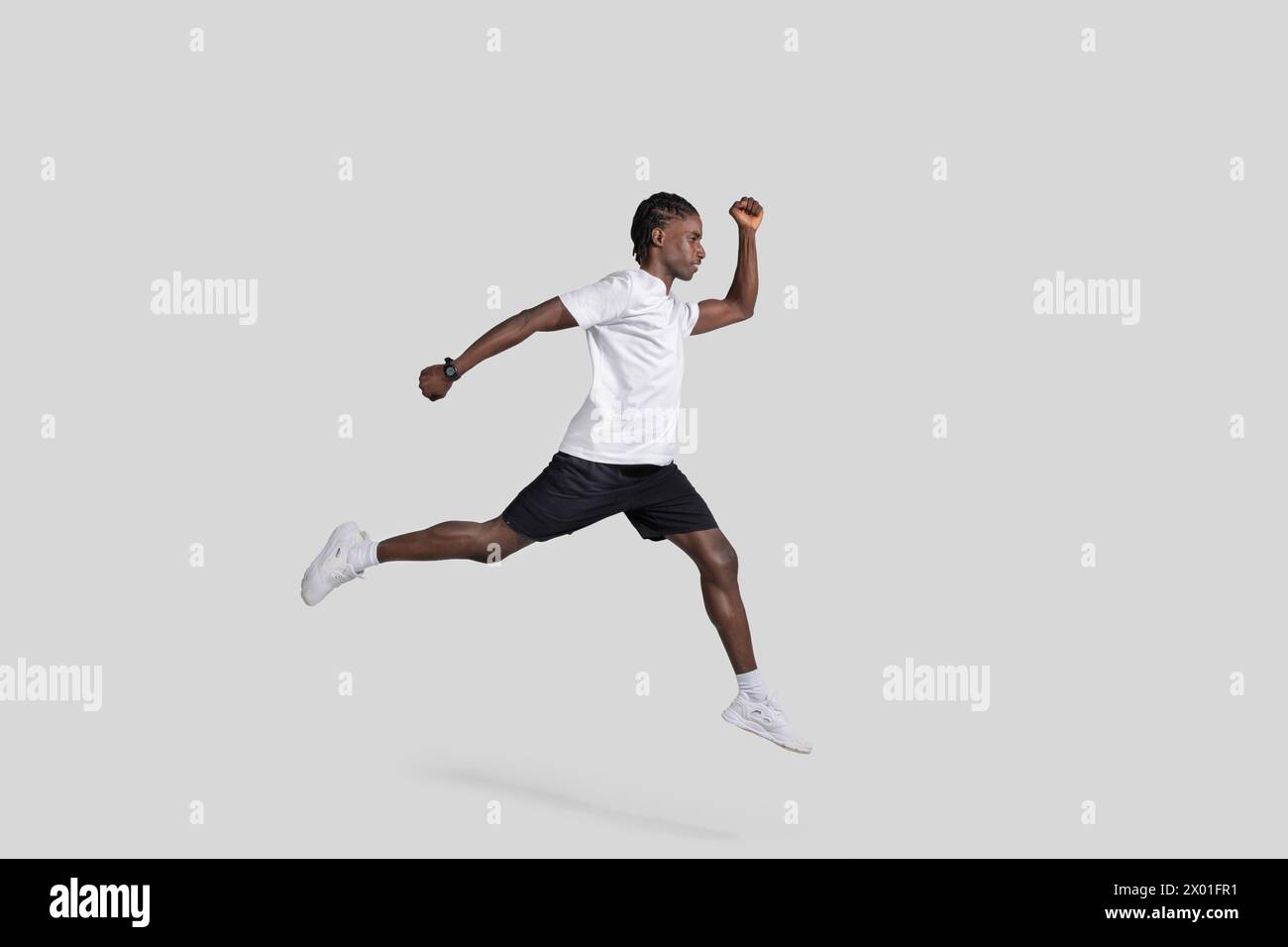 Athletic man in mid-air running pose on grey Stock Photo - Alamy