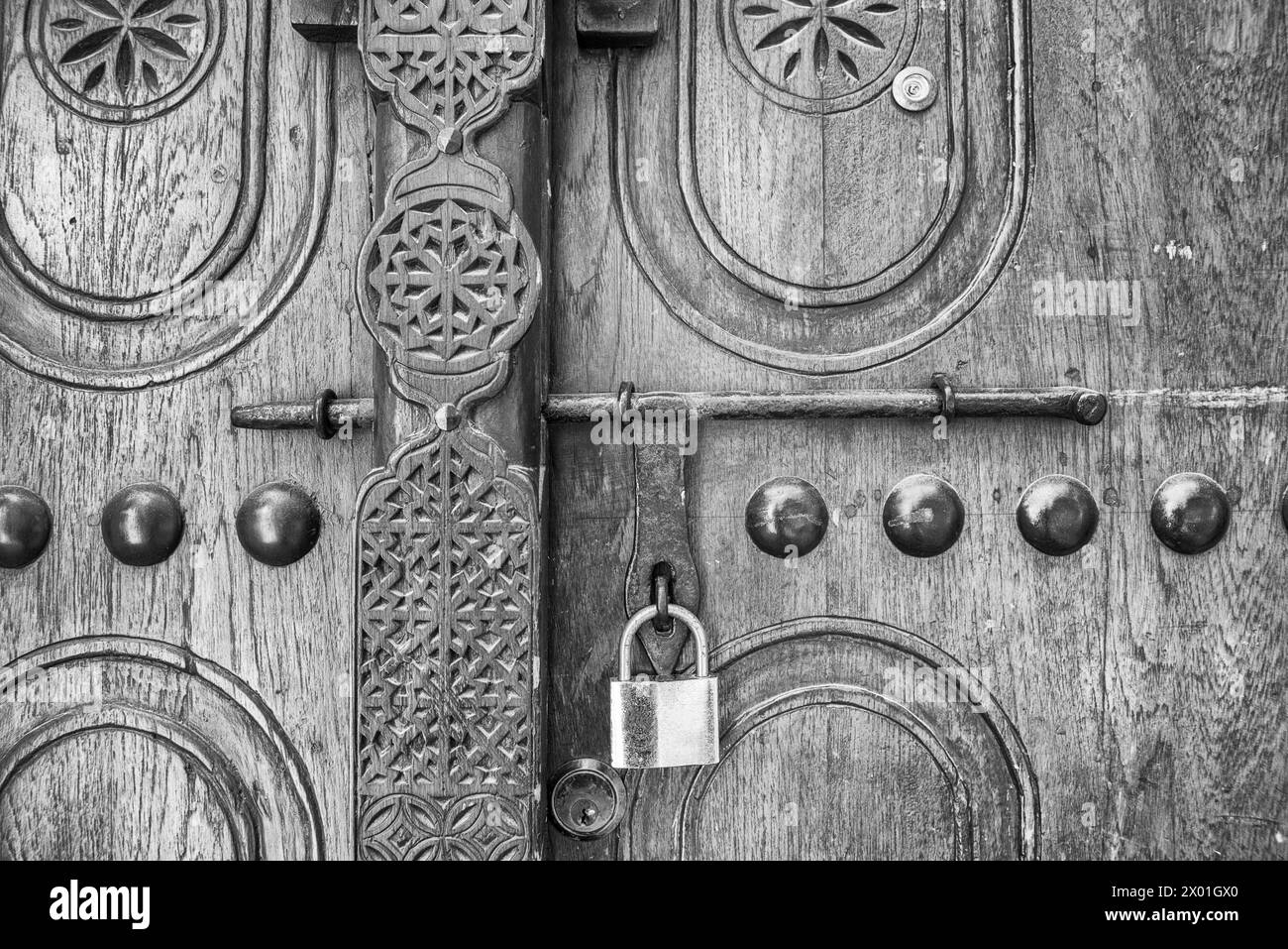 Monochrome image of detail of a carved wooden door and lock at the ...