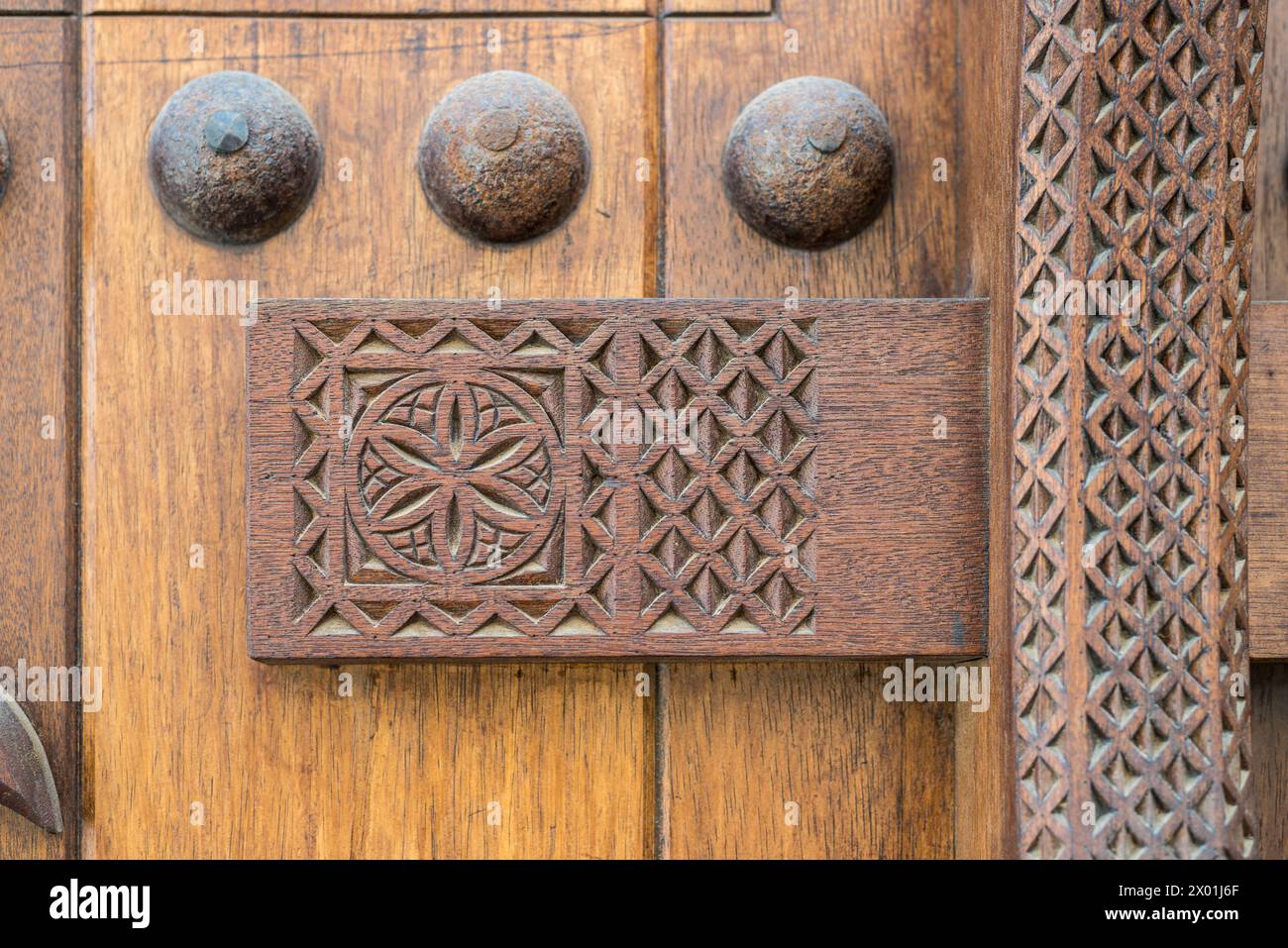 Narrow-focus detail of a carved wooden door lock at the entrance to a ...