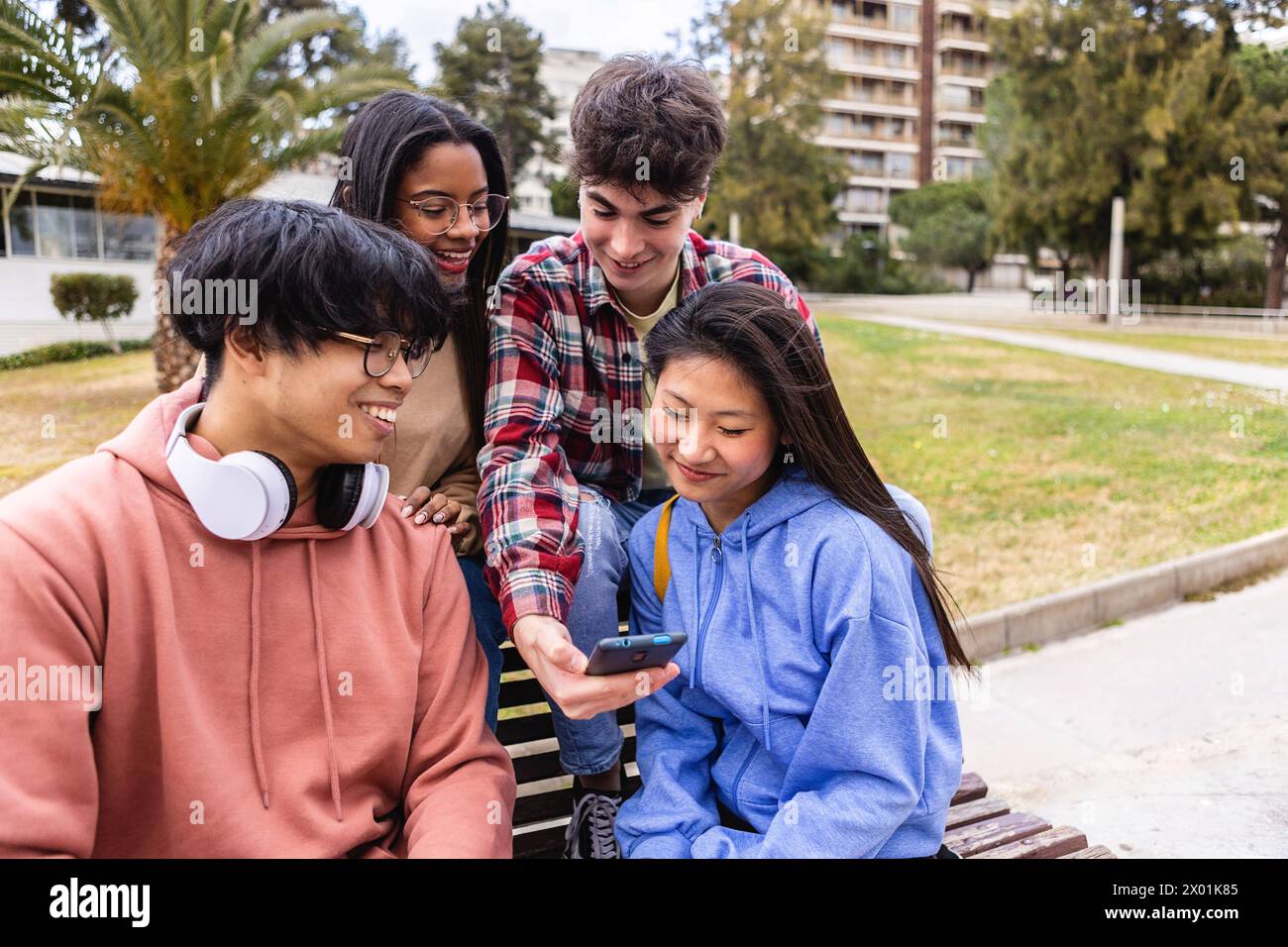 Happy student friends using mobile phone together sitting at college ...