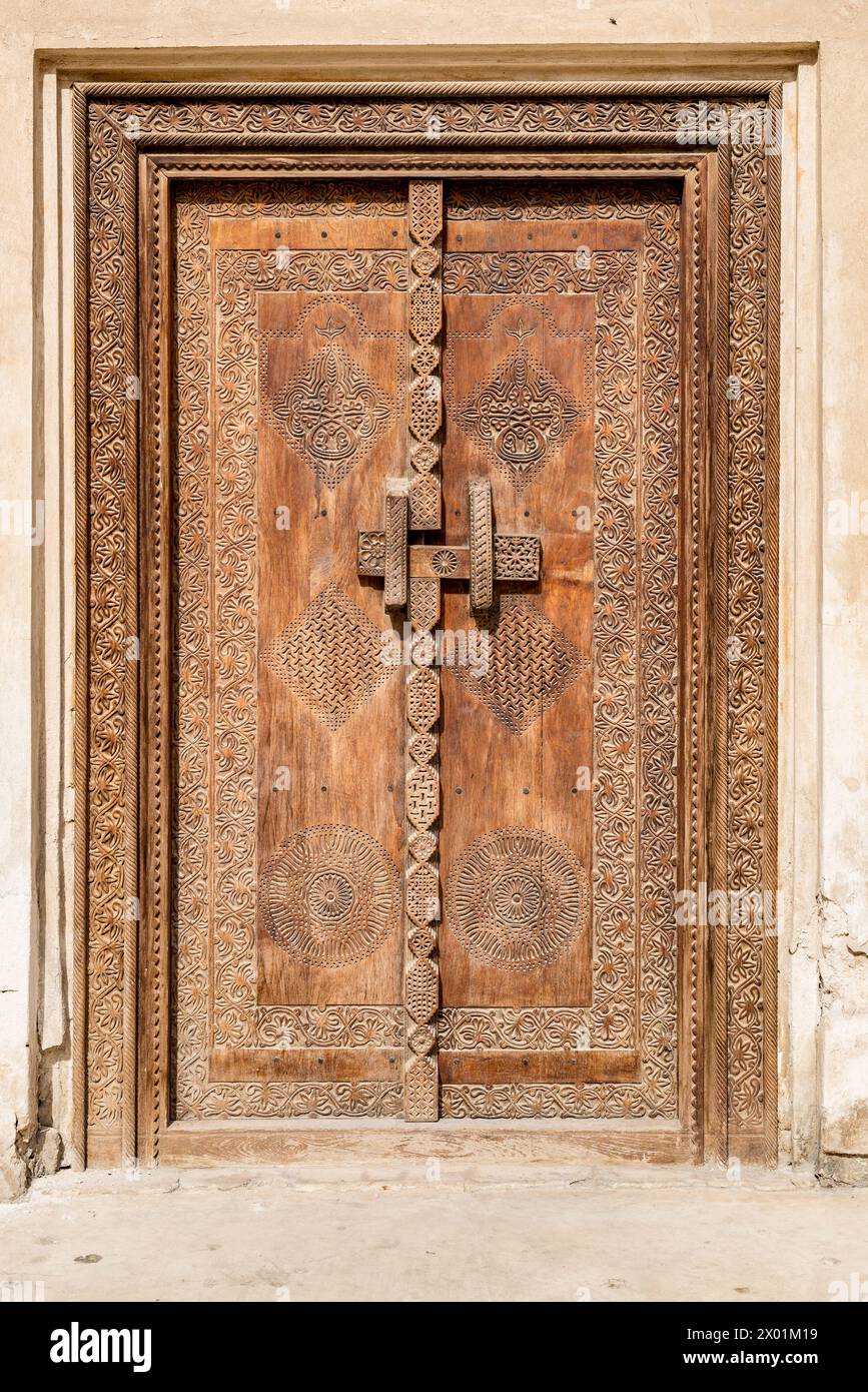 A carved wooden door at the entrance to a restored traditional arabian ...