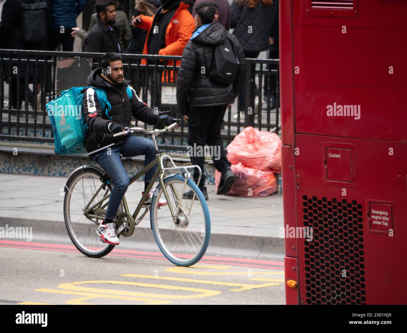 Deliveroo Food delivery cyclist, in Central London riding behind a bus ...