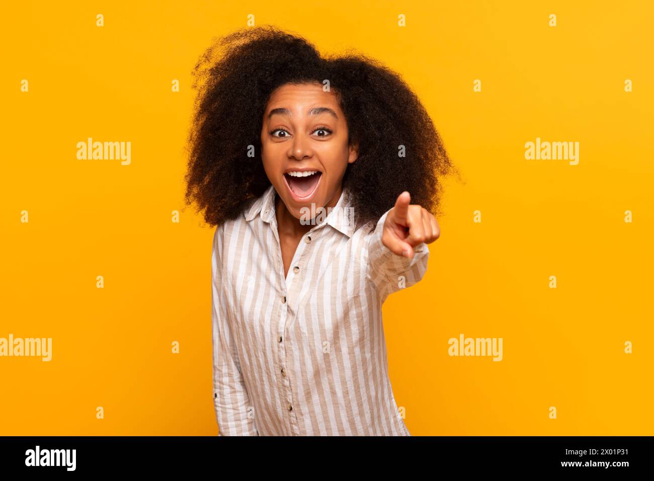 Excited woman pointing forward on yellow background Stock Photo - Alamy