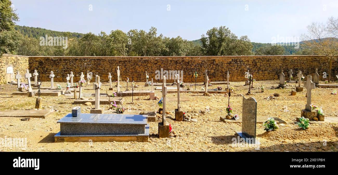 A cemetery with many graves and a large stone wall. The cemetery is empty and quiet. Scene is ...