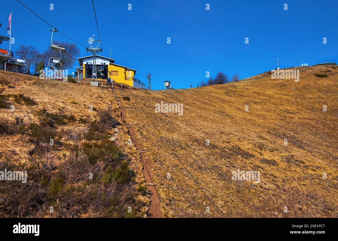 The dried up yellow slope and upper station of the chair lift atop ...