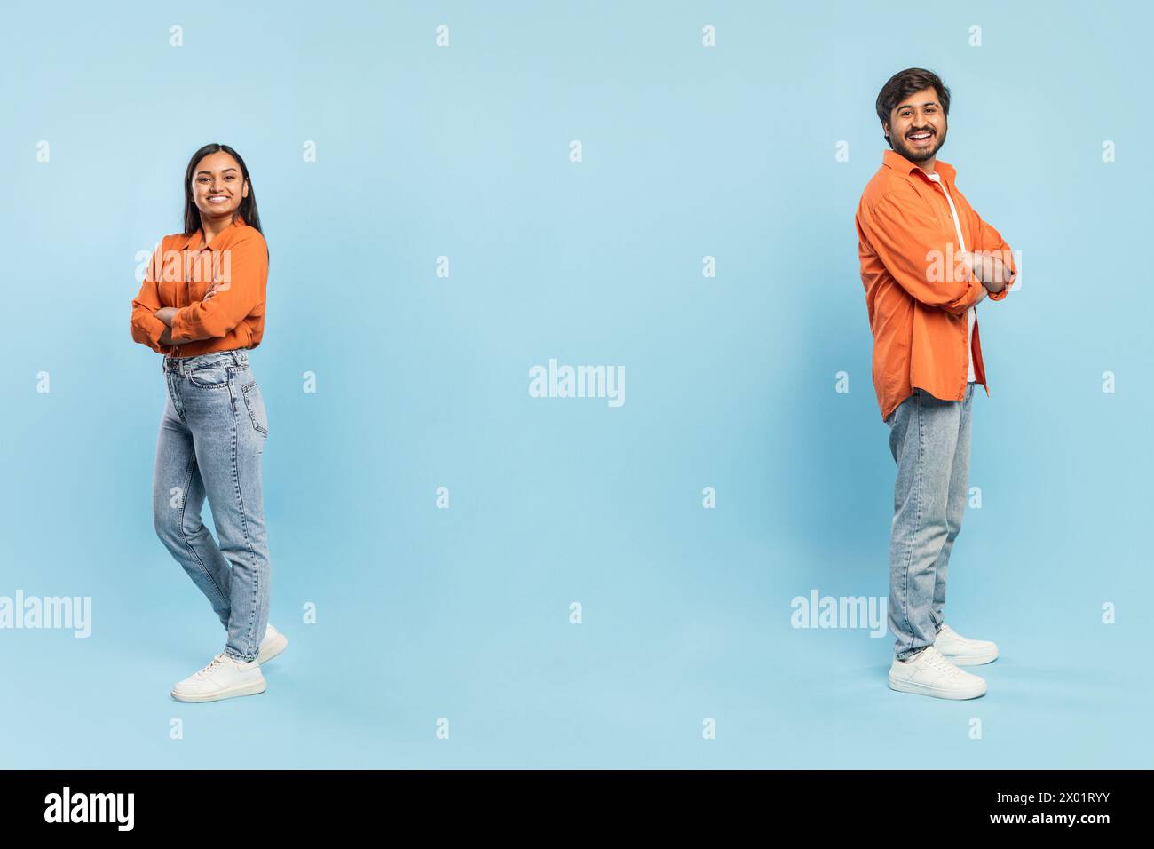 Couple standing back-to-back with confident poses on blue background ...
