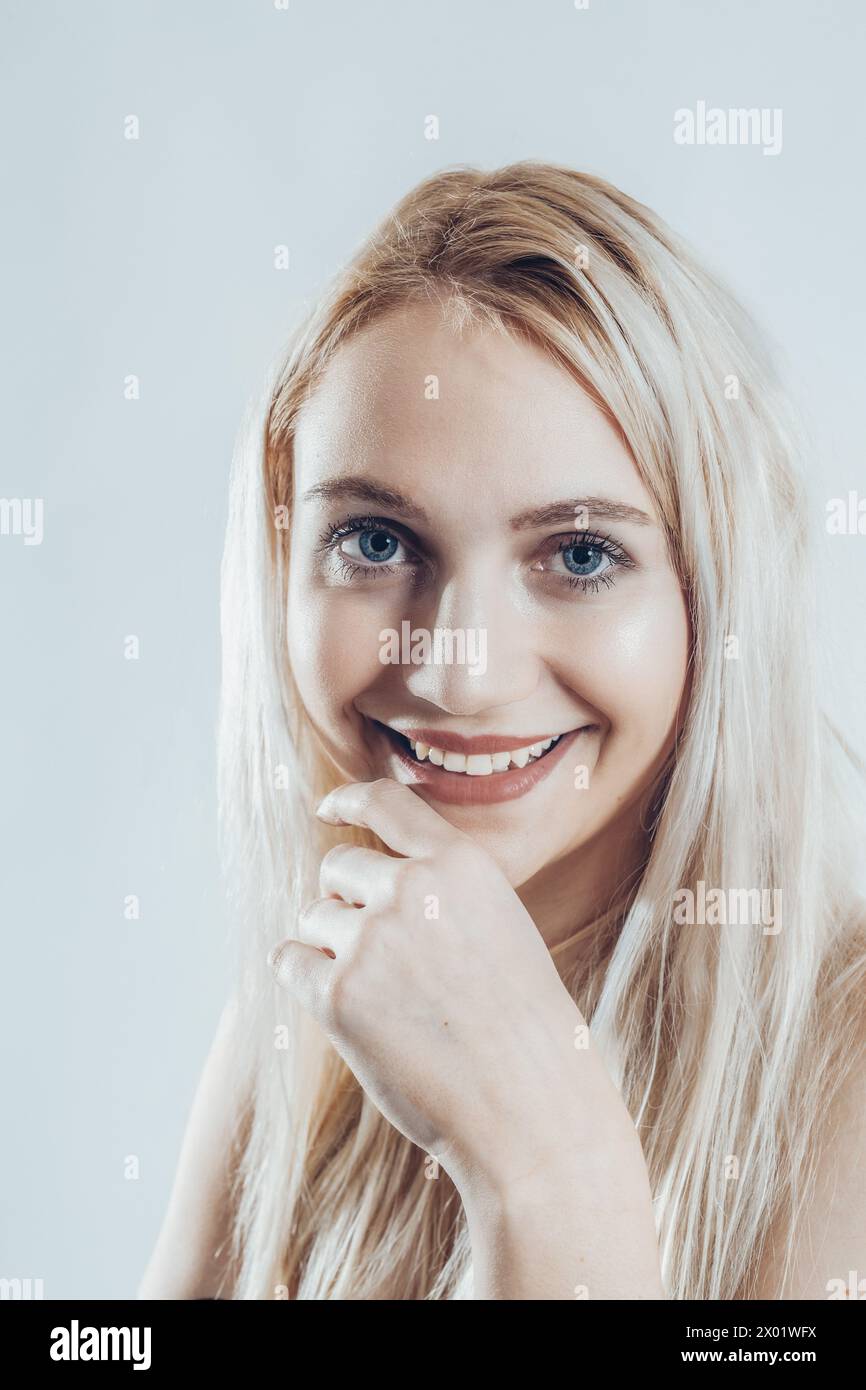A woman stands in front of a pristine white background and smiles ...
