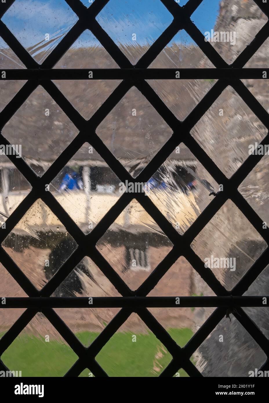 Looking across the courtyard, through an old leaded window with old ...