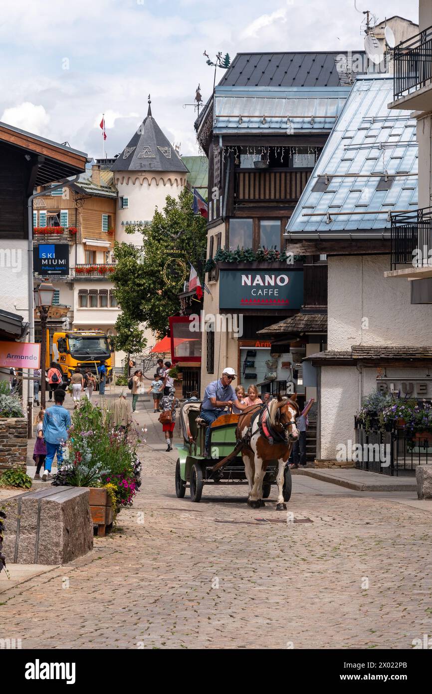 Horse-drawn carriage with tourists in the centre of the alpine village ...