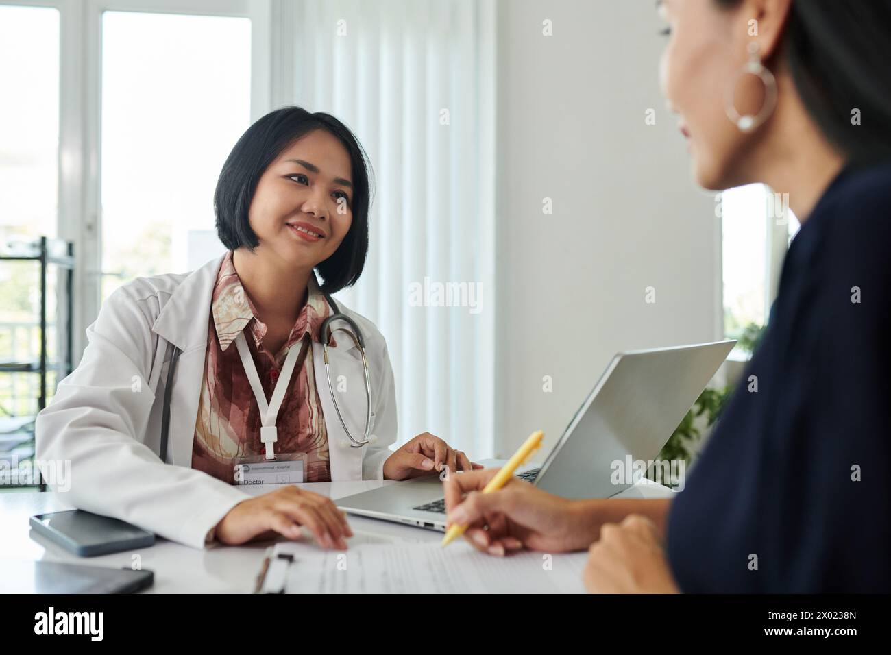 Smiling doctor asking patient specific questions when she is filling ...