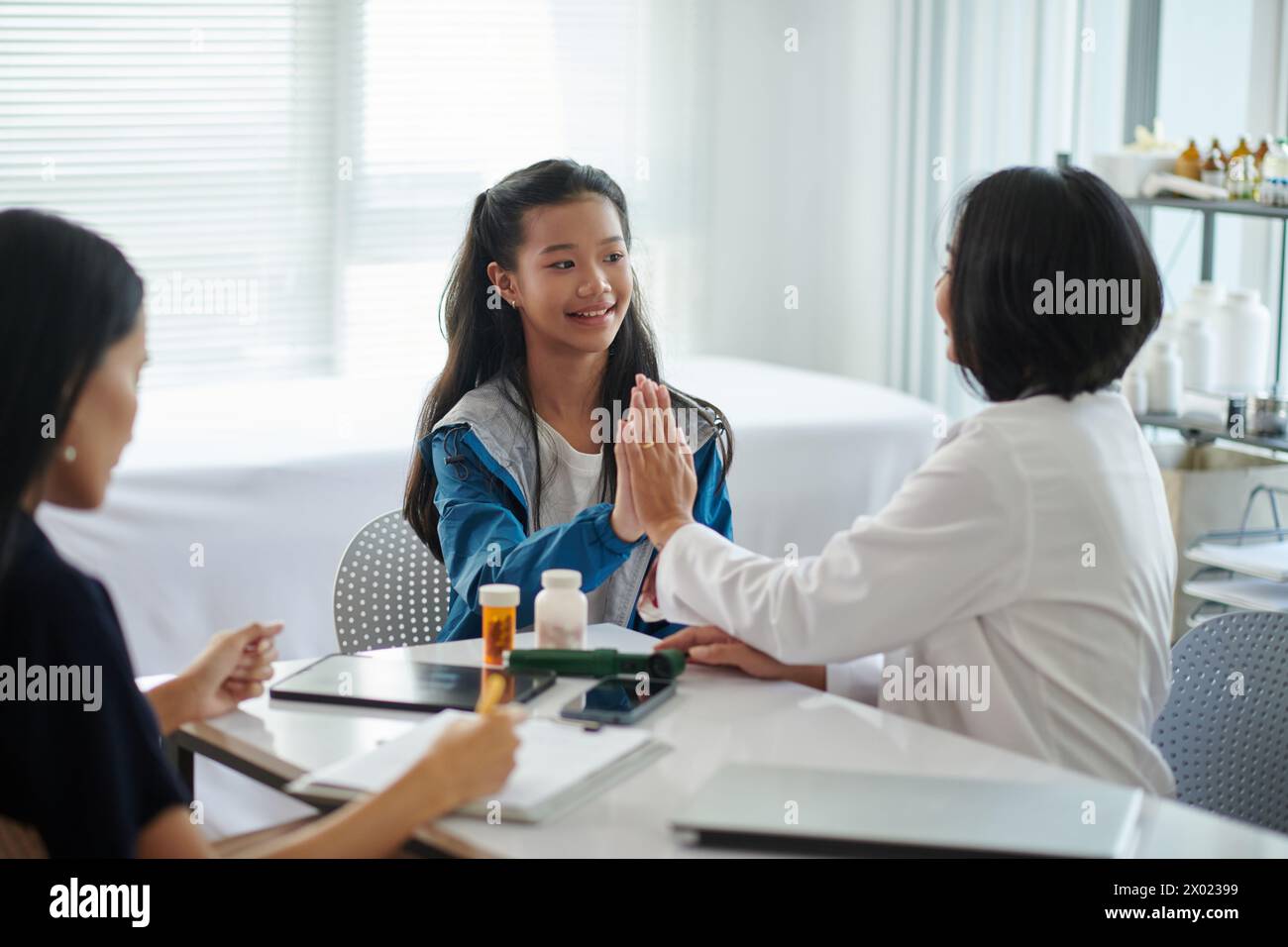 Smiling Vietnamese teenage girl giving high five her therapist ...