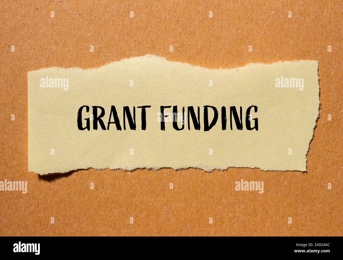 Grant funding words written on ripped paper with cardboard background ...