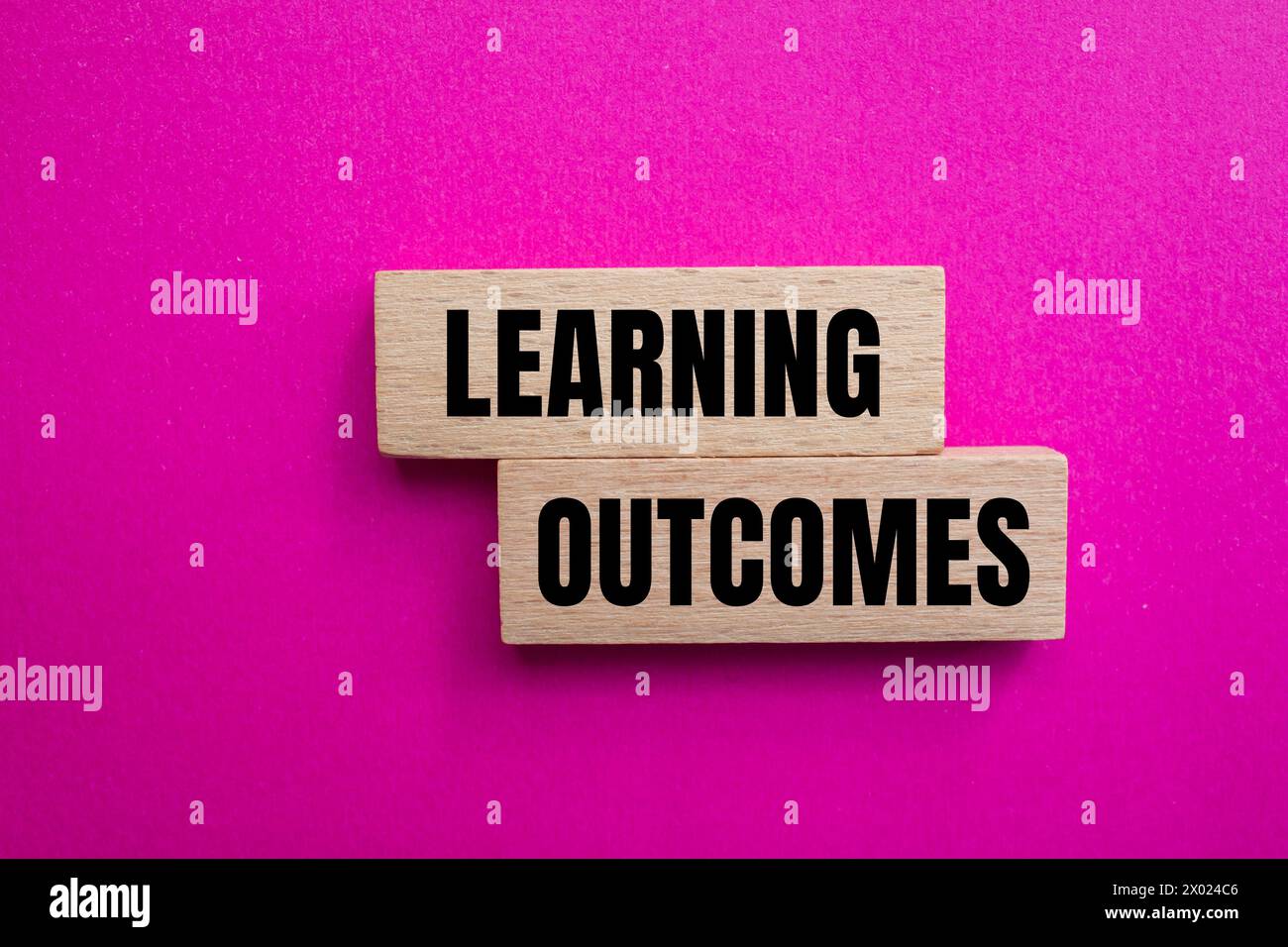 Learning outcomes words written on wooden blocks with pink background ...