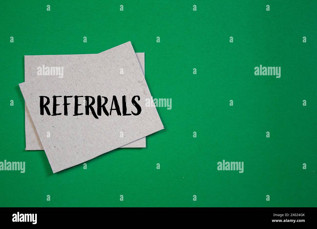 Referrals word written on ripped paper with green background ...