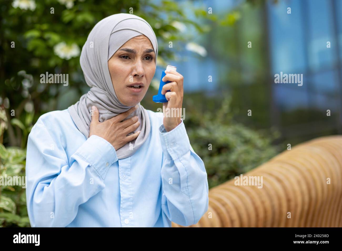 Shocked arabic woman covering neck with hand and holding bronchial ...