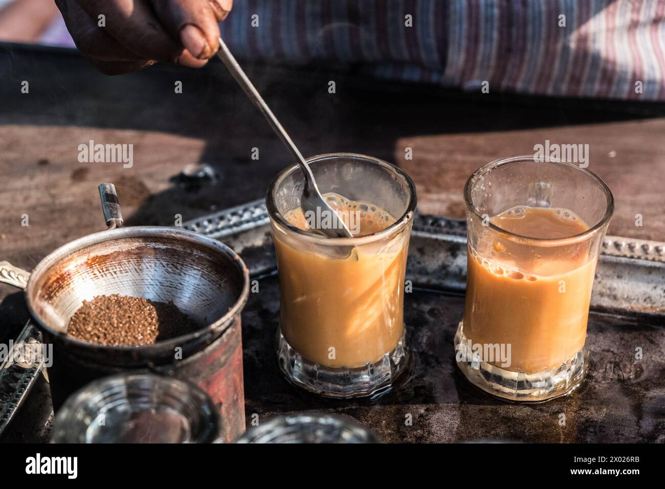 Hot milky tea in glasses being stirred on a tray at a tea stall Stock ...