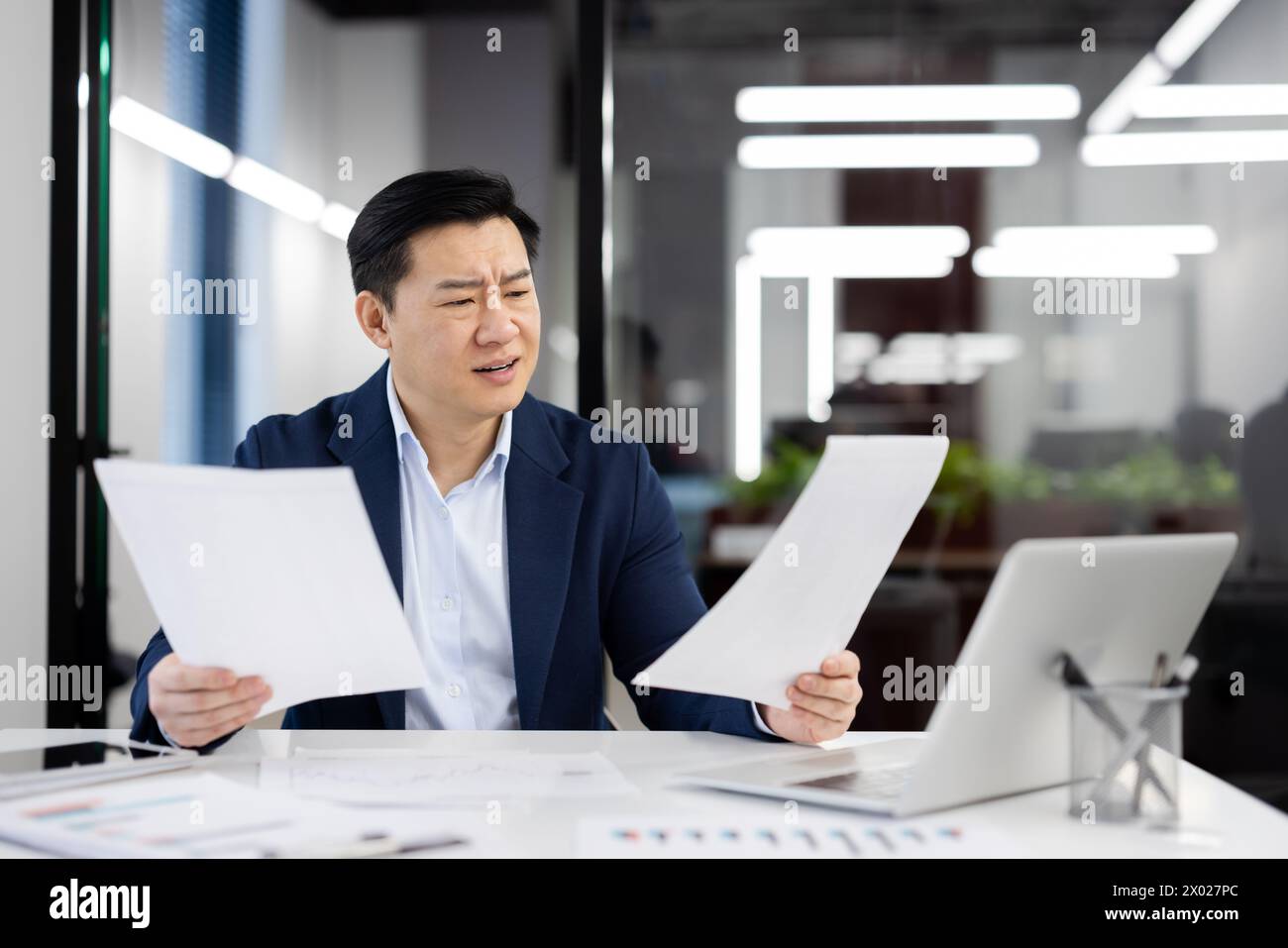 Puzzled chinese financial director looking amazingly in legal documents ...
