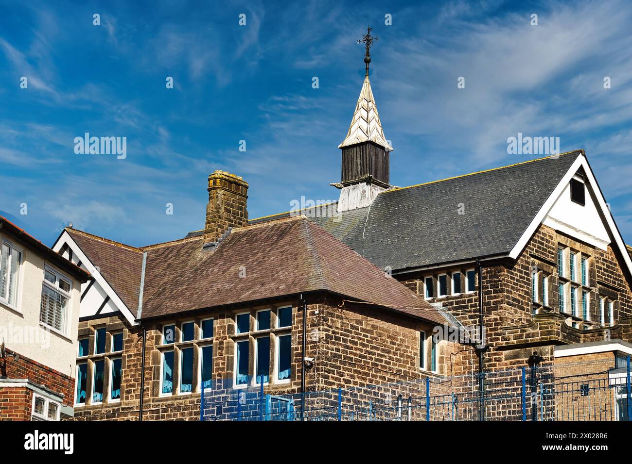 Traditional brick school building with a spire against a blue sky with ...