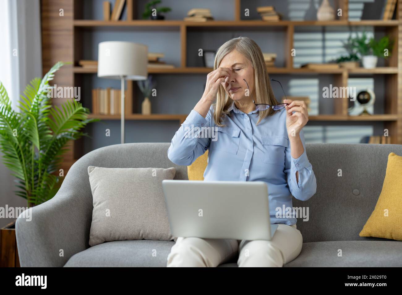 Elderly remote worker holding portable computer on laps while taking ...